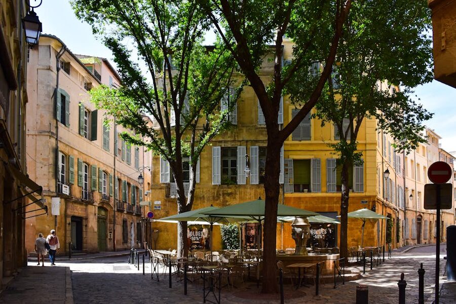Sunlit Aix-en-Provence street corner with café tables