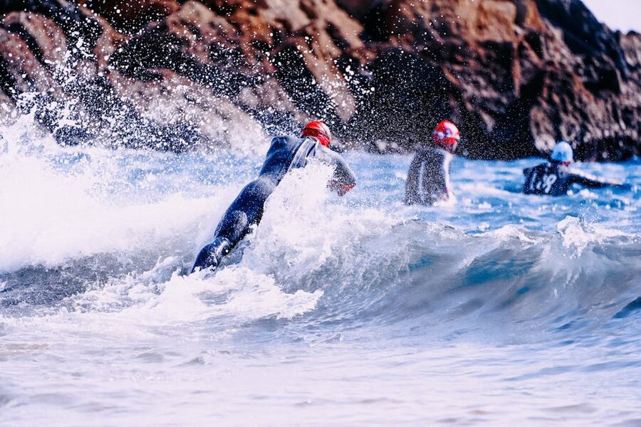 Swimmers in wetsuits entering ocean from a boat