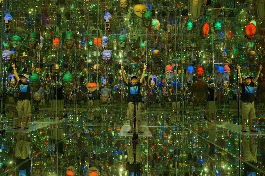 Child exploring mirror room with colorful masks and lights