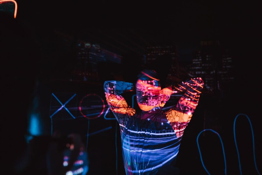 Person in dark room illuminated by neon projections futuristic
