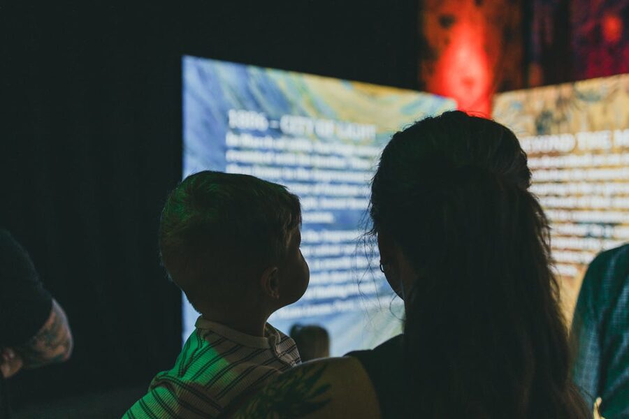 Woman and child observing digital art and text on illuminated screens
