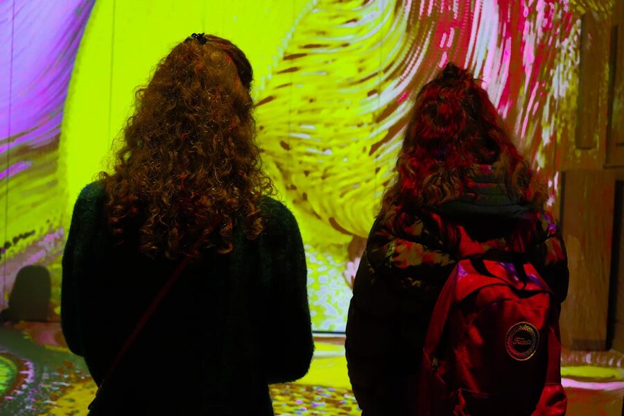 Two women observing colorful projections in art gallery