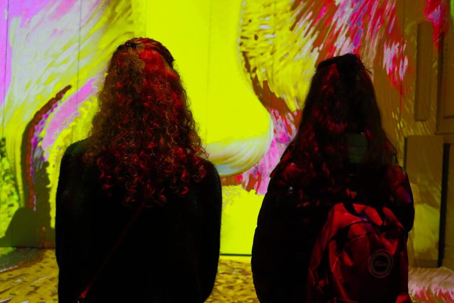 Two women viewing colorful digital art in museum setting