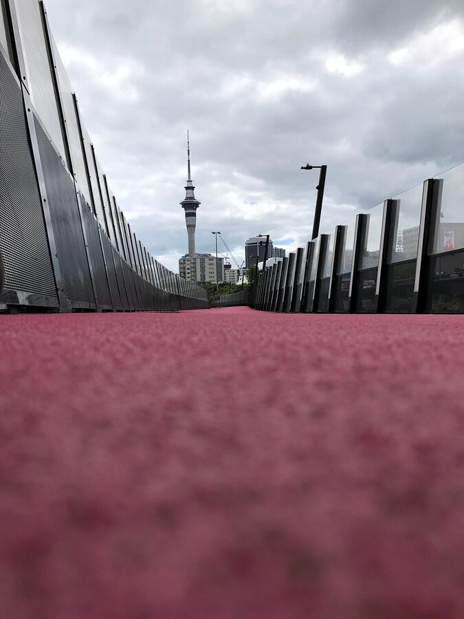 Auckland Sky Tower with the pink Lightpath cycleway at sunset