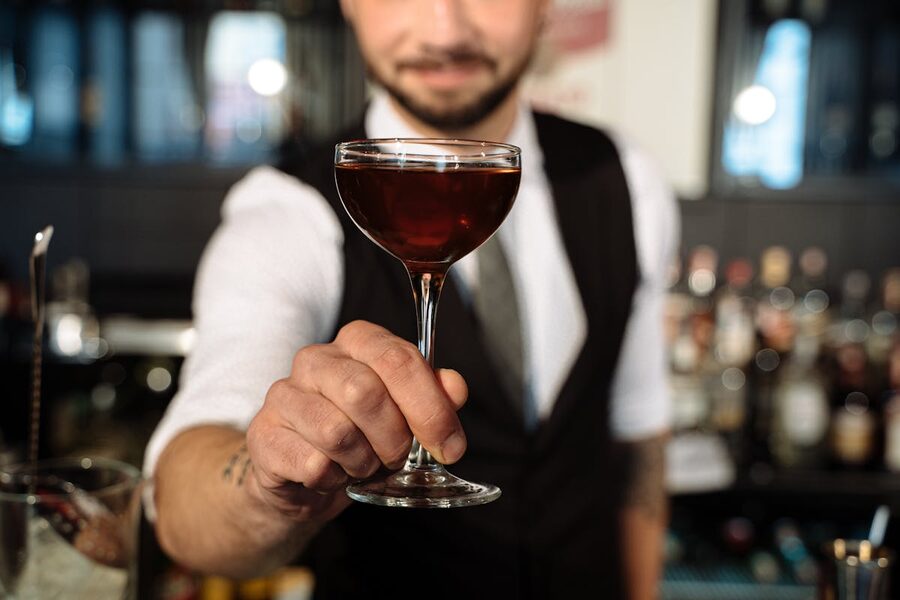 Bartender handing a cocktail across a bar counter