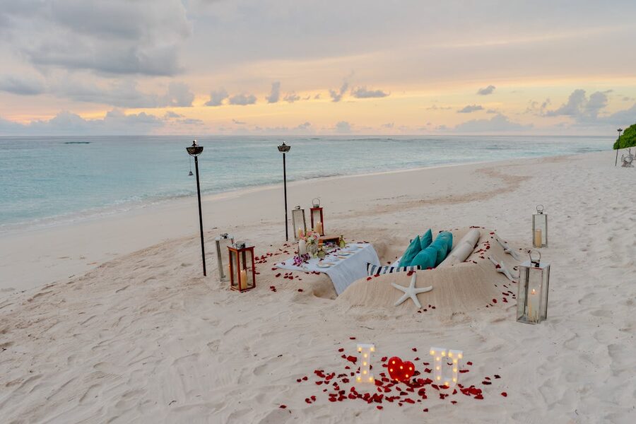 Intimate beach dining setup with glowing candles and ocean view at sunset