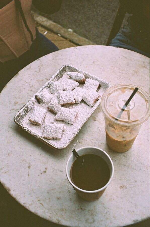 Overhead shot of powdered beignets with hot and iced coffee on a cafe table
