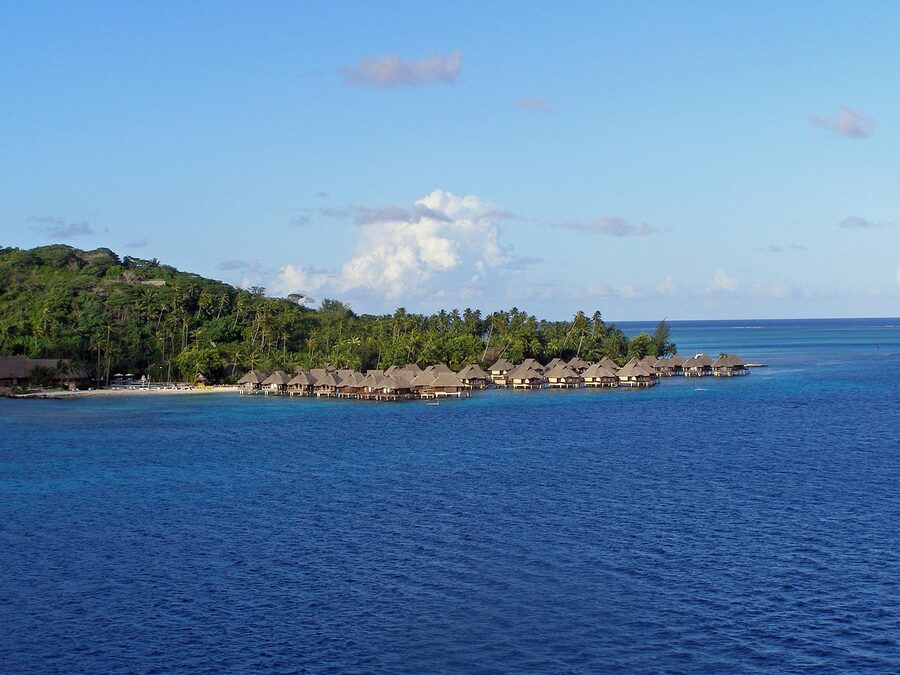 Overwater bungalows on Bora Bora lagoon with the green main island in the back