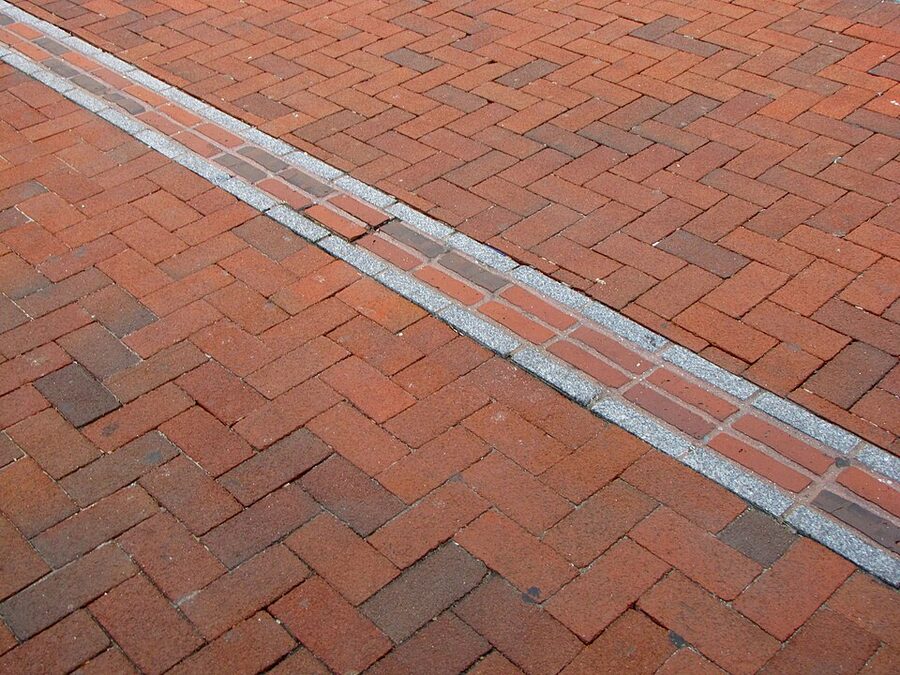 Red brick Freedom Trail marker path set into the sidewalk in Boston