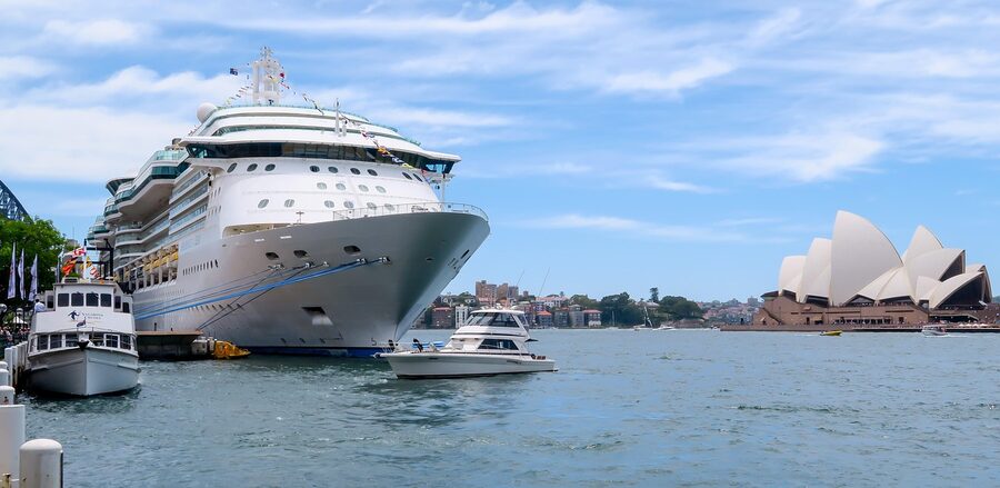 A cruise ship passing beneath the Sydney Harbour Bridge with the Opera House