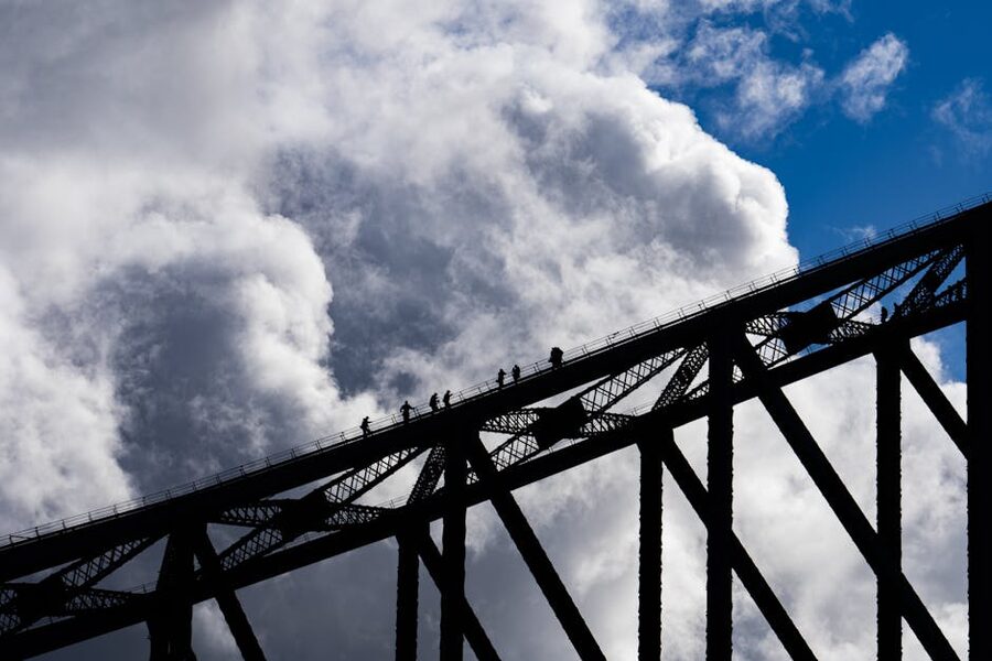 Silhouetted BridgeClimb climbers on the Sydney Harbour Bridge arch at sunset