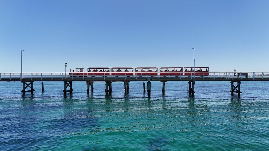 Red Busselton jetty train running over turquoise water in Western Australia