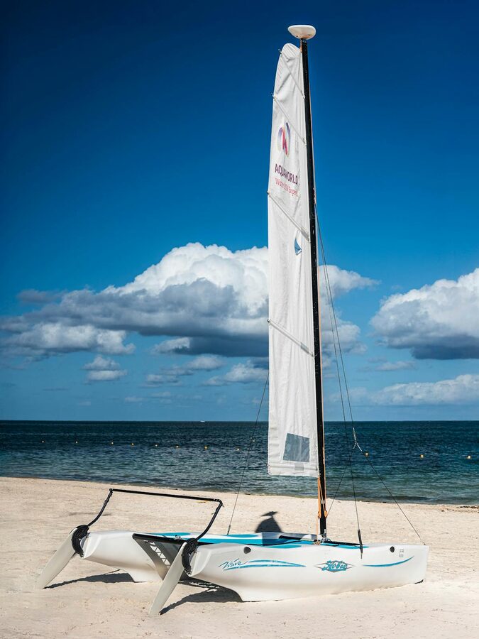 White catamaran resting on a sandy beach against blue sky and ocean