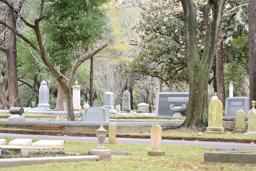 Peaceful cemetery scene with tombstones surrounded by lush trees