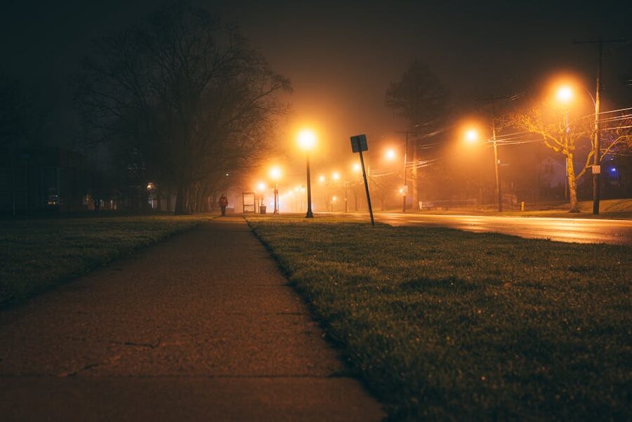 Moody foggy night street with glowing streetlights, atmosphere for a ghost tour