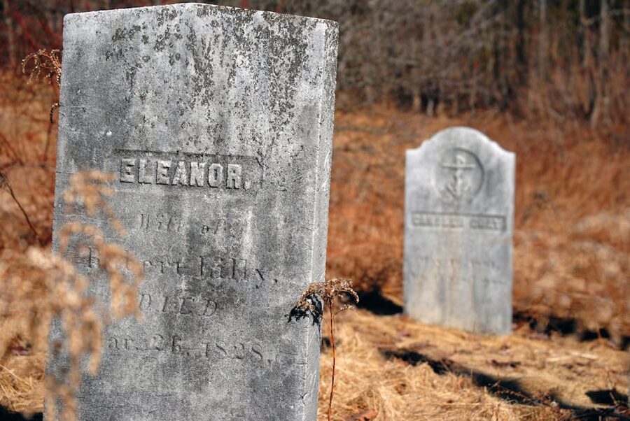 Weathered tombstones in an overgrown historical cemetery in autumn