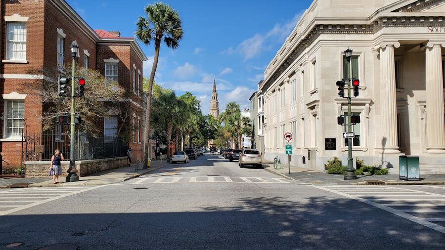 Sunny Charleston street with historic buildings and church spire in distance