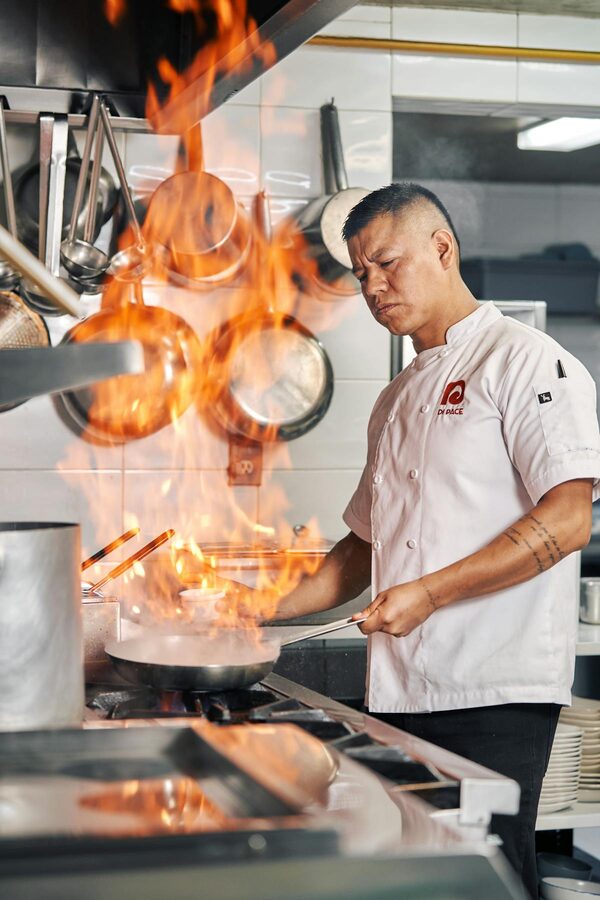Chef expertly handles fire while cooking in a professional kitchen