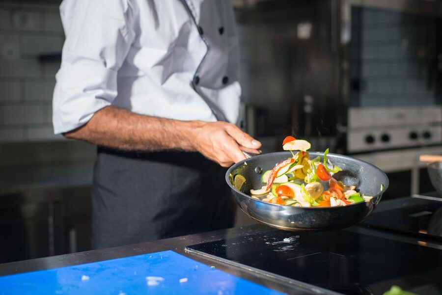 Professional chef tossing fresh vegetables in a frying pan