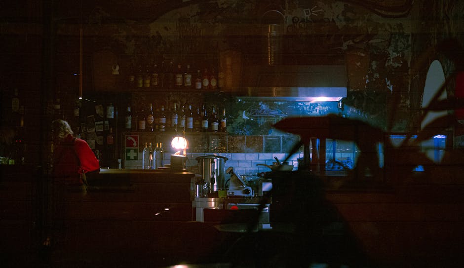 Dimly lit bar with bottles on shelves creating a moody atmosphere