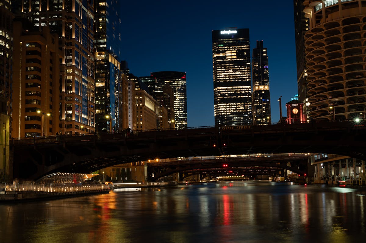 Chicago skyscrapers and river at night with reflections and lit-up bridge