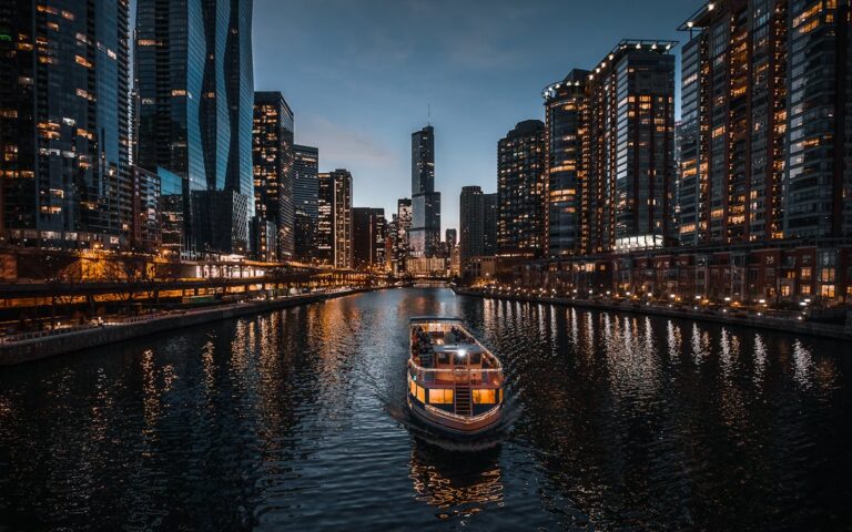 Chicago skyline at dusk with reflections on the river and a boat cruising past