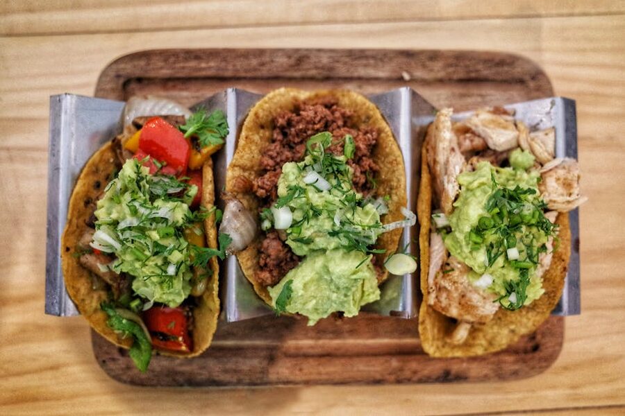 Three tacos with fresh guacamole and garnishes