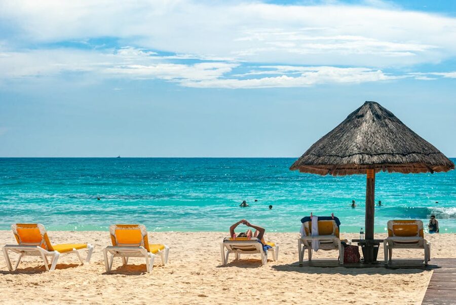 Row of blue sun loungers and thatched palapa on a Mexican beach