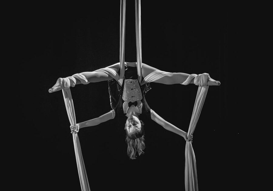 Aerial silk artist performing inverted in black and white