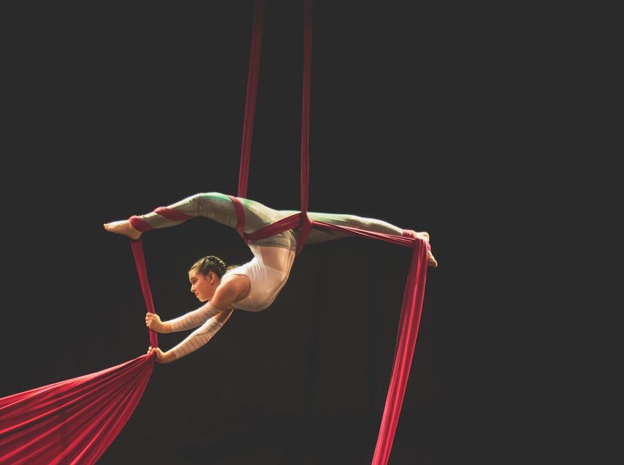 Aerial silk performer on red silks showcasing acrobatics