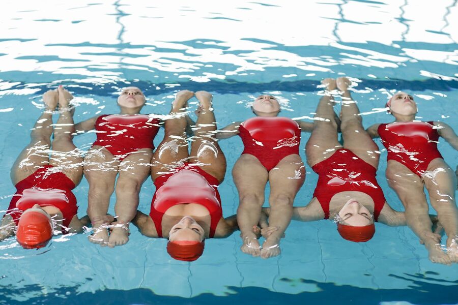 Synchronized swimming team performing routine in pool