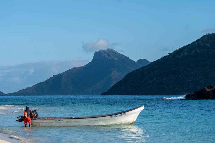 Fiji beach with a boat against a mountainous backdrop