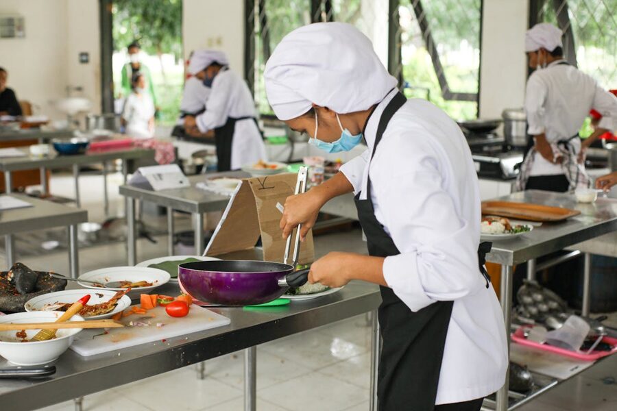 Culinary students in uniforms practicing cooking in a professional kitchen