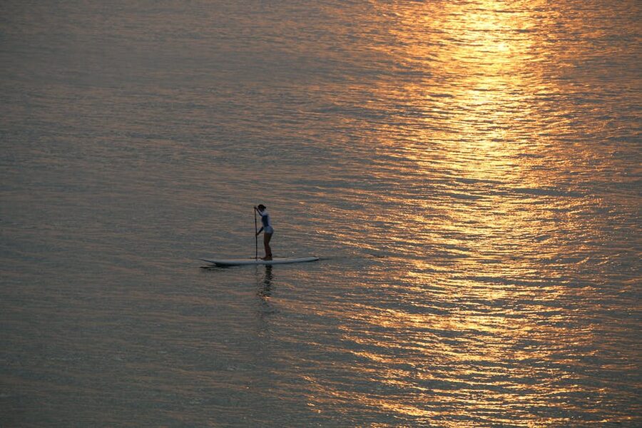 Paddleboarder at sunset with golden reflection on water