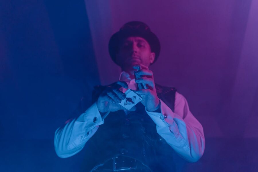 Magician showcasing card trick under colorful lighting