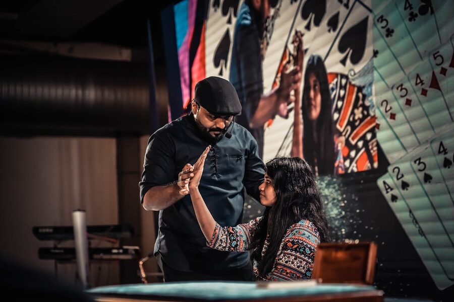 Magician performing card trick with assistant on stage