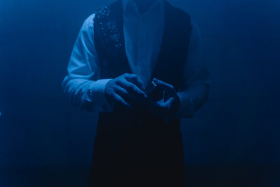 Magician performing card trick under blue lighting