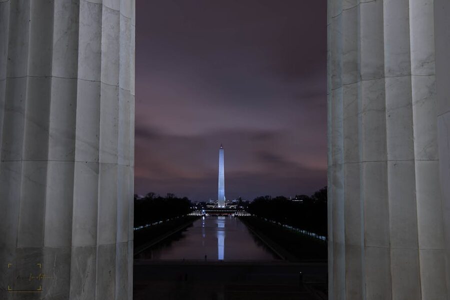 Washington Monument framed by Lincoln Memorial columns at night
