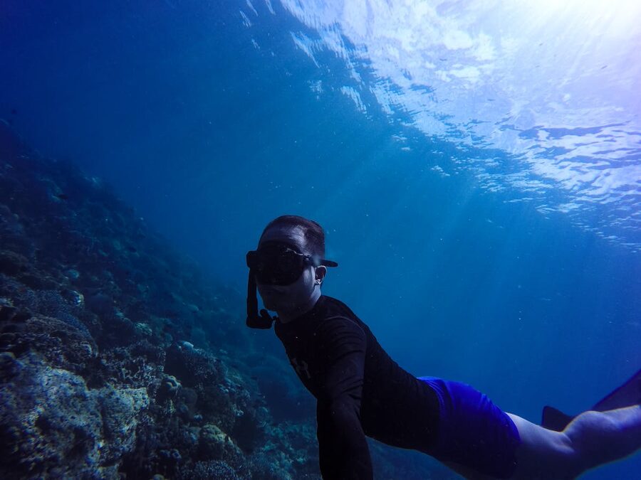 Diver exploring coral reef in clear blue underwater scenery