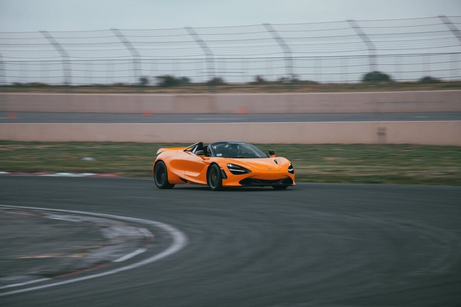 Orange McLaren sports car speeding around racetrack