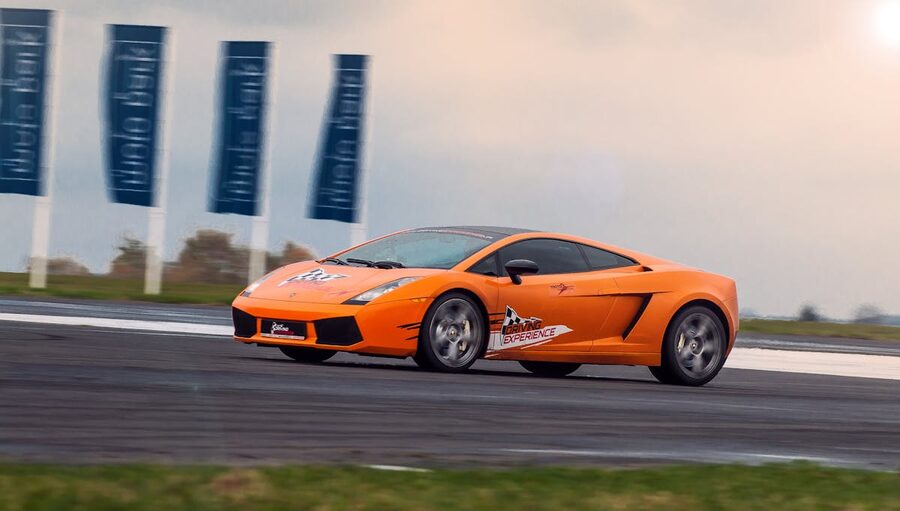 Orange luxury sports car riding fast on highway at speed