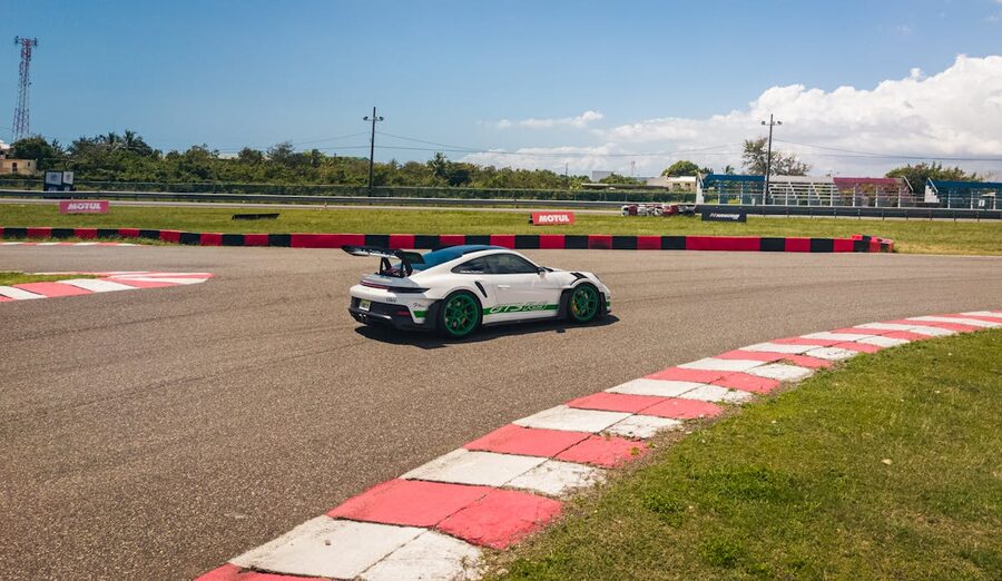 Sports car maneuvering racetrack curve under bright sky