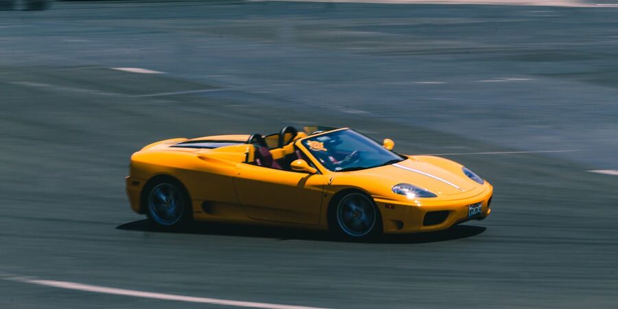 Yellow convertible sports car speeding on racetrack