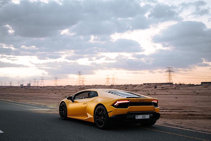 Yellow Lamborghini Huracan on scenic desert road at sunset