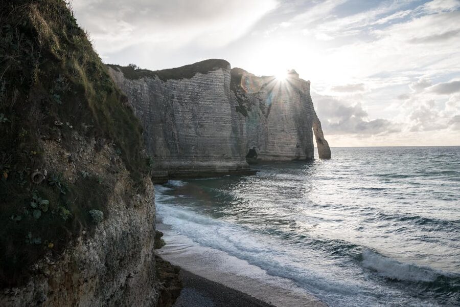 Sunlit cliffs of Etretat with waves crashing on shore
