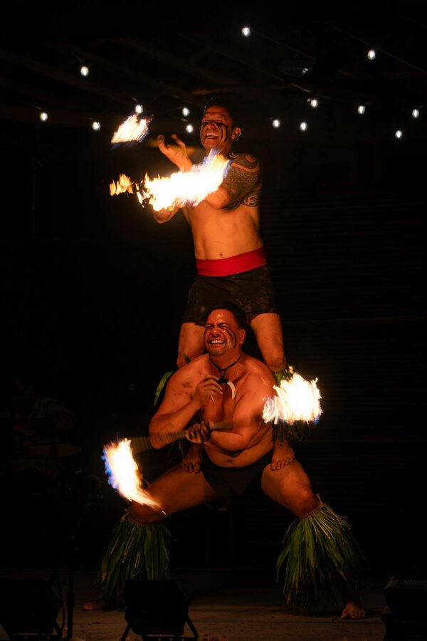Two men performing a fire dance act at a Hawaiian night show