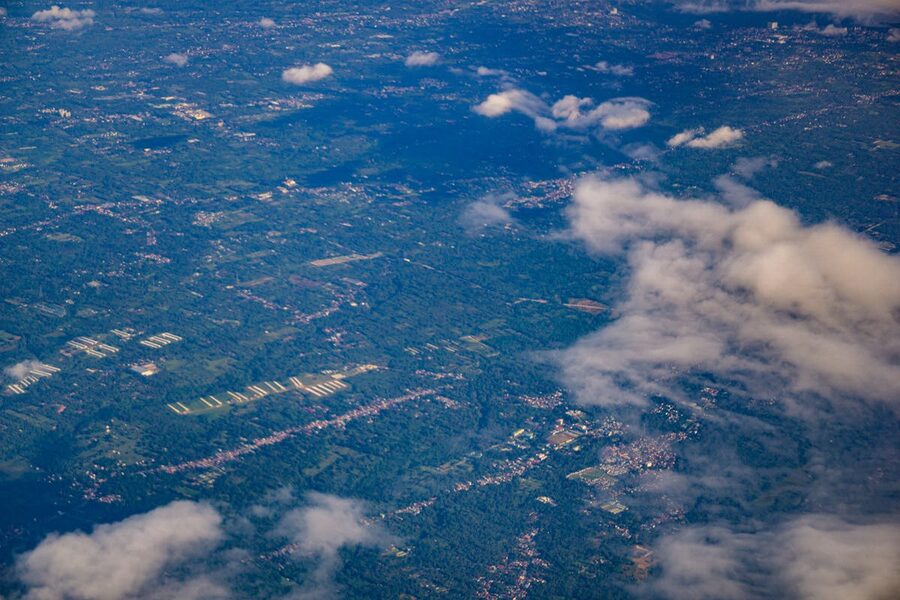 Aerial shot of green landscapes and clouds from above