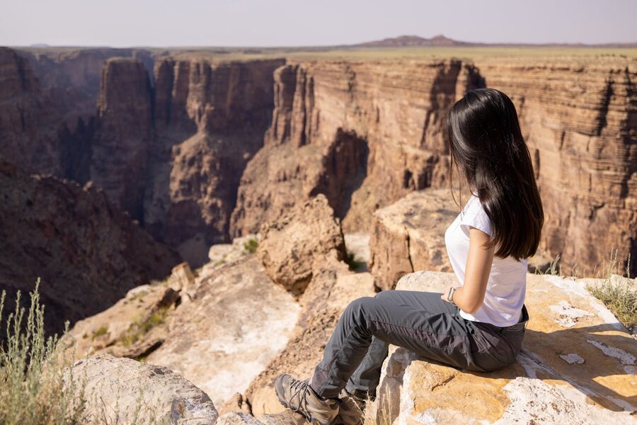 Woman sitting on cliff edge at Grand Canyon viewpoint taking in the view
