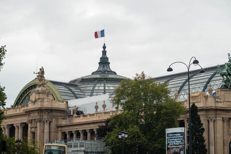 Grand Palais Paris glass dome and French flag against blue sky