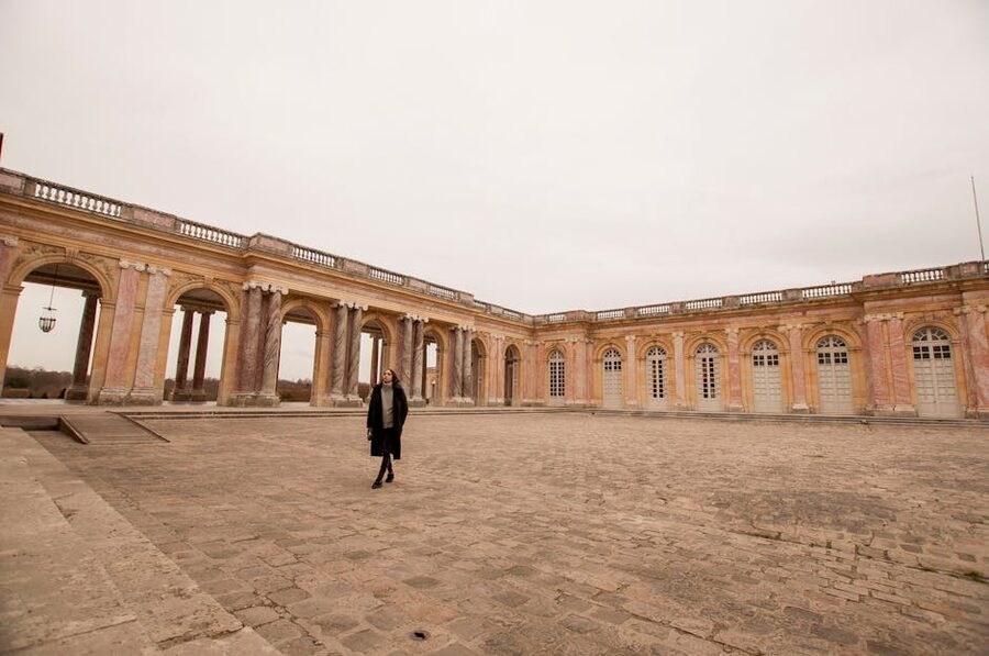 A woman walks through the historic courtyard of the Grand Trianon Palace in Versailles, France
